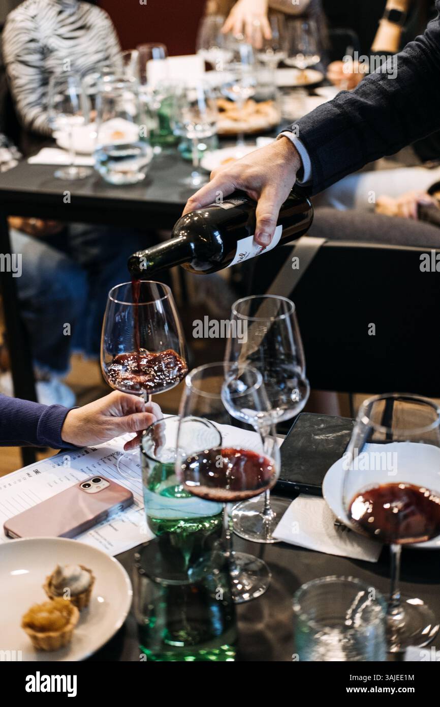 Pouring wine into glasses at a formal group tasting event. Community ...