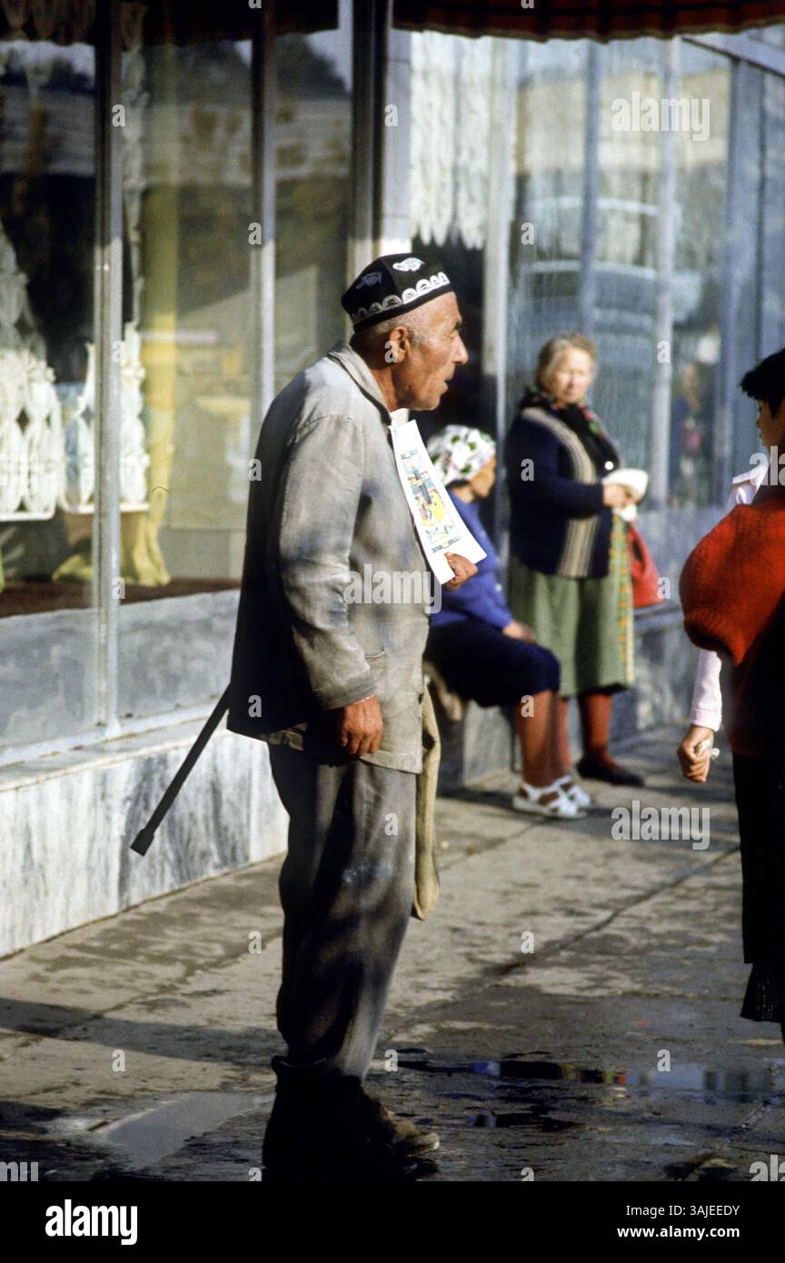 old man advertising with a printed product in the old town of Tashkent ...