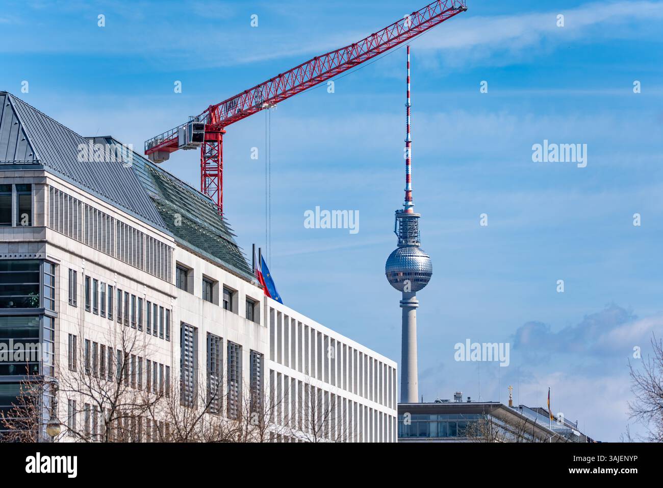 A tall building with a crane on top. A tall television tower in the ...