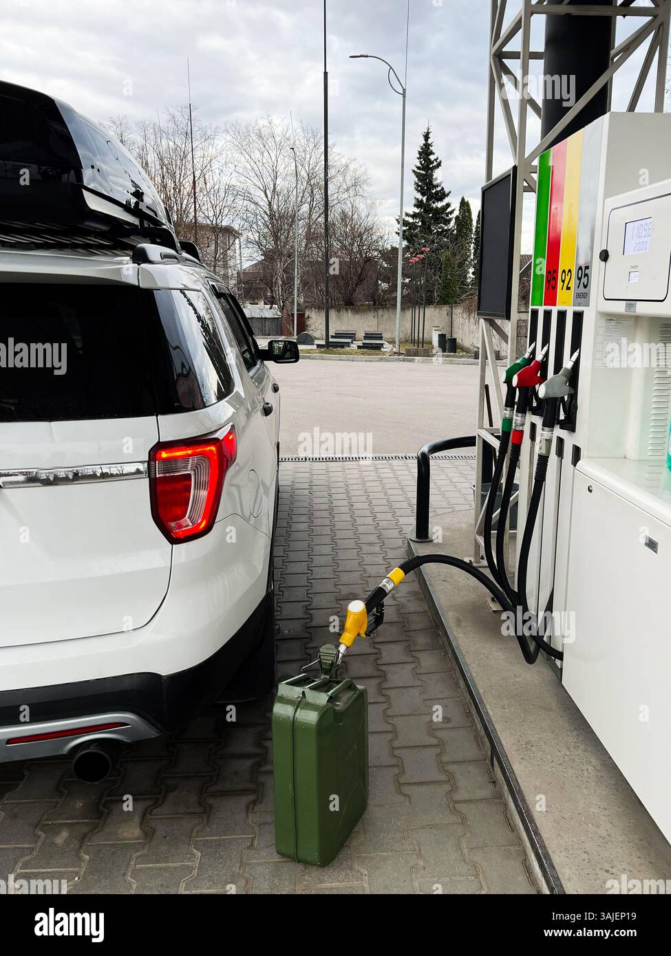 A vehicle being refueled at a petrol station using a large green jerry ...