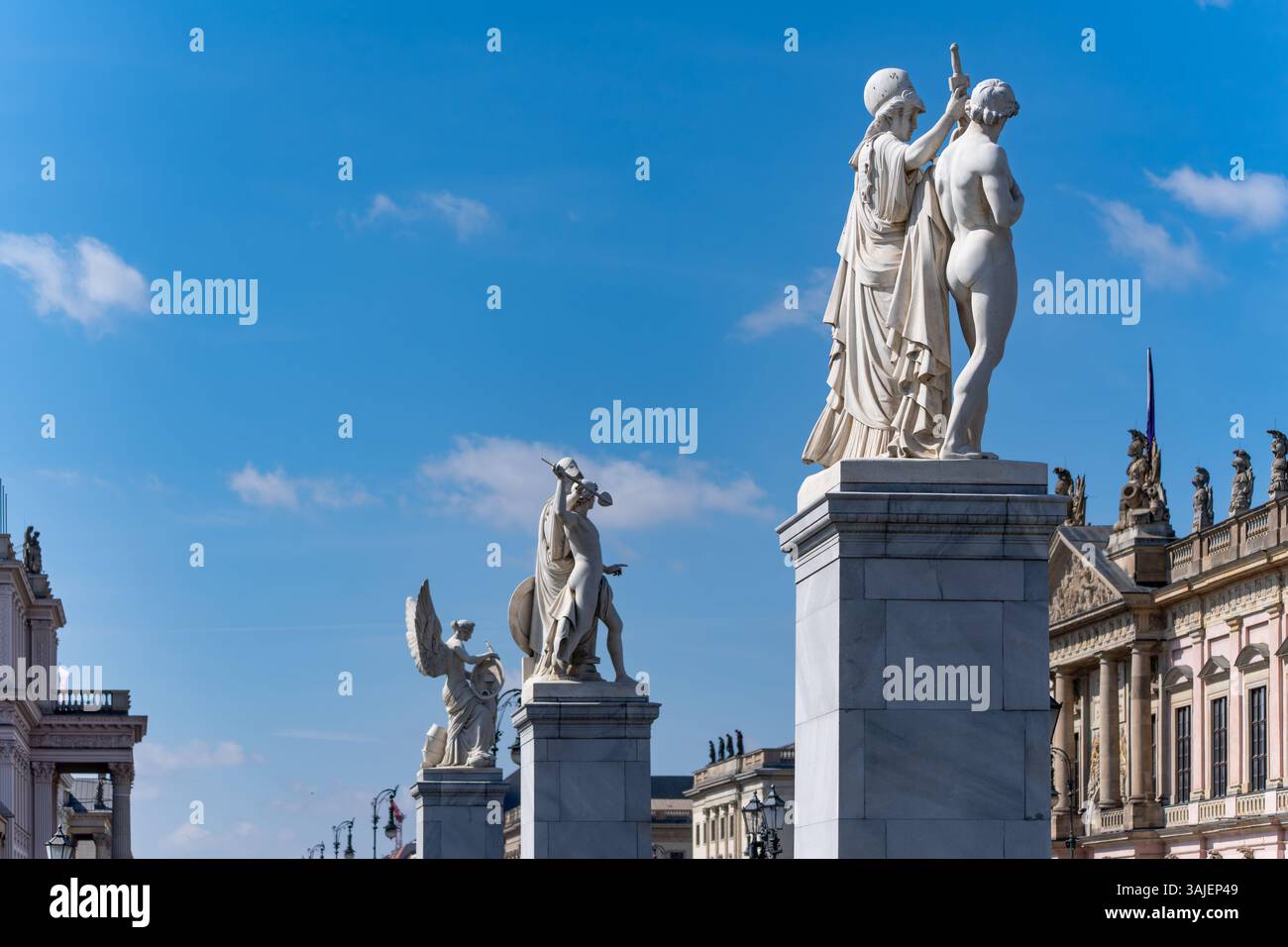Three statues are on top of a stone pillar. One of the statues is of a ...