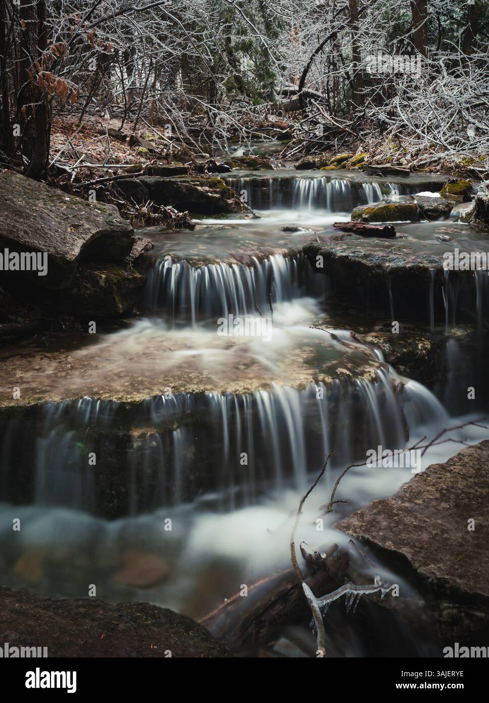 Long exposure of waterfalls running through woods on winter day Stock ...