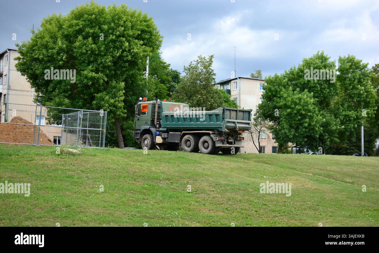 Dumper truck standing on grass in city area. Dump truck standing next ...