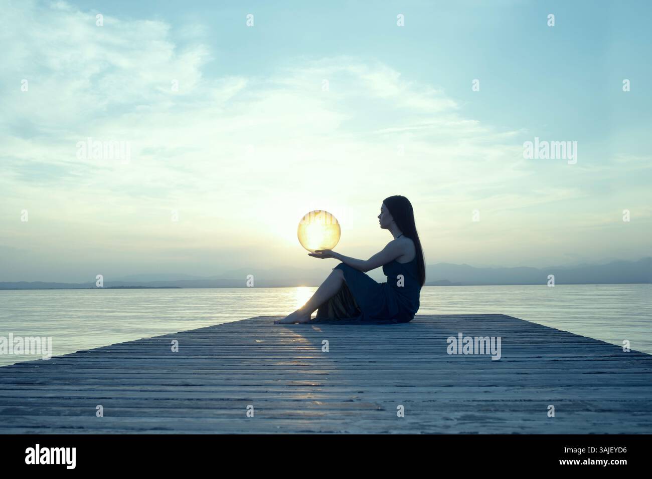 Female figure in backlight holding a moon-shaped lamp in front of a ...