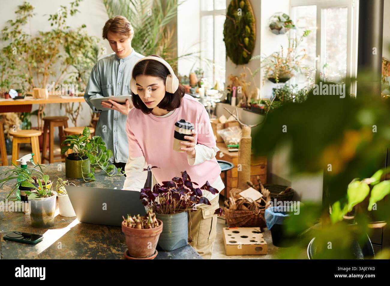 Two creatives engage in art activities in a thriving, plant filled ...