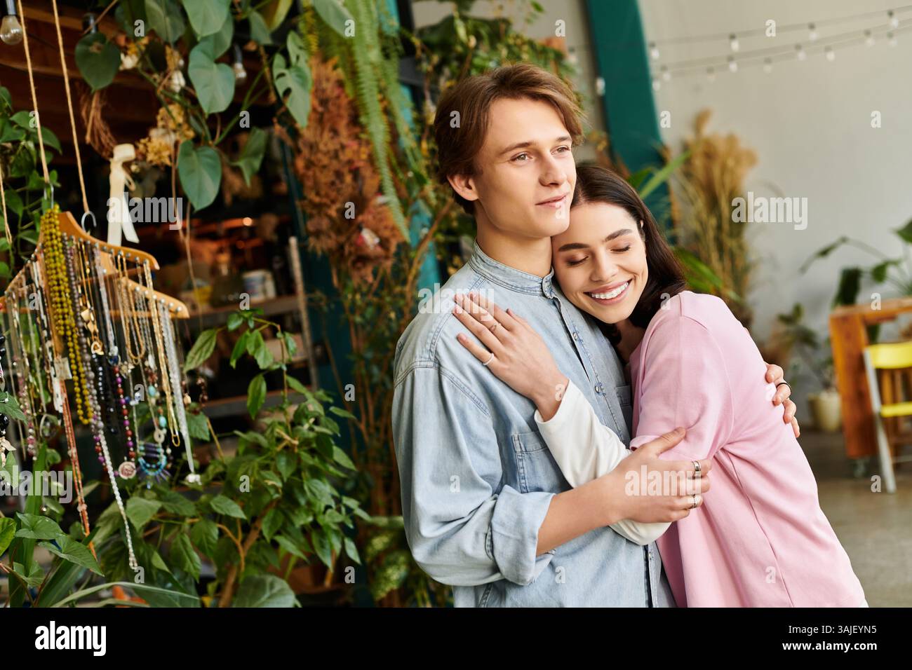Creative couple embrace in a bright art studio adorned with plants ...