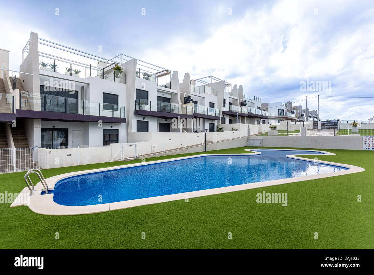 Bright blue communal pool in a landscaped area with modern apartments ...