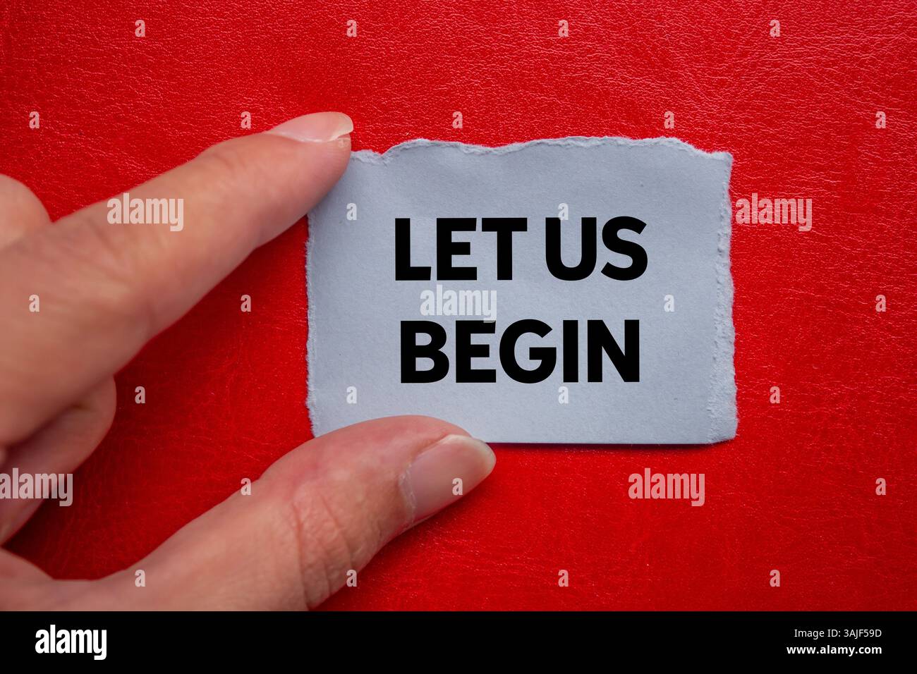 Let us begin message written on ripped torn grey paper piece on red ...