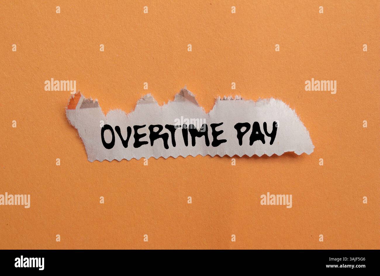 Overtime pay message written on ripped torn newspaper piece on orange ...