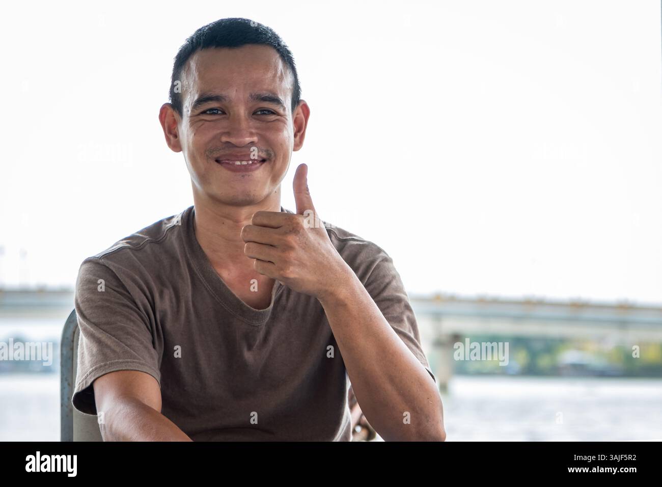 Happy young vietnamese man on a tour boat taking tourists by the river ...