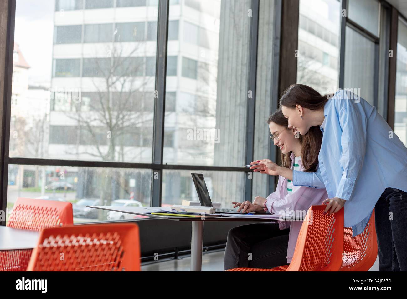 Two young female students work together on the laptop in the university ...