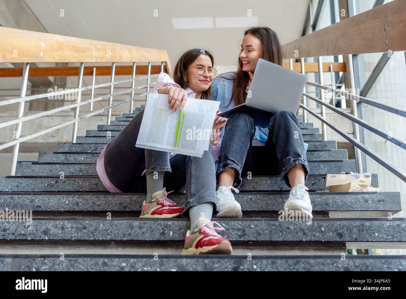 Low angle view with two female students sitting on the university ...
