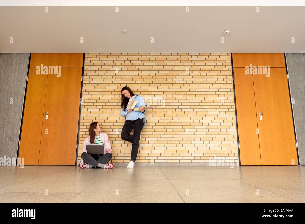 Female students studying using laptop and books in the university lobby Stock Photo - Alamy