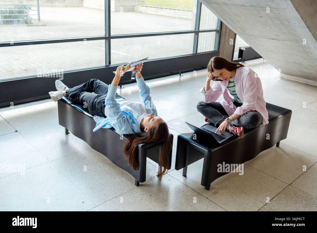 Female students studying together in the university hallway, sitting ...