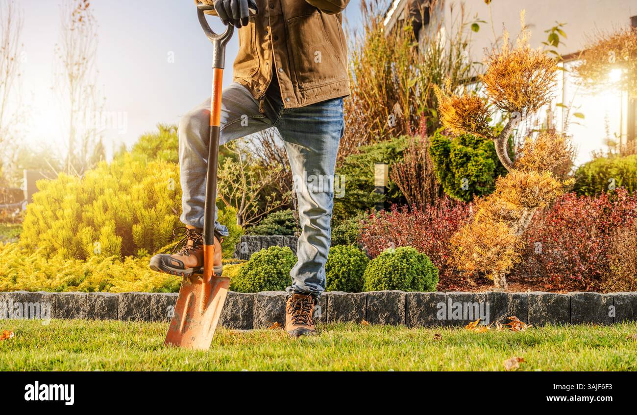 A person in a brown jacket is actively digging into the soil with a ...