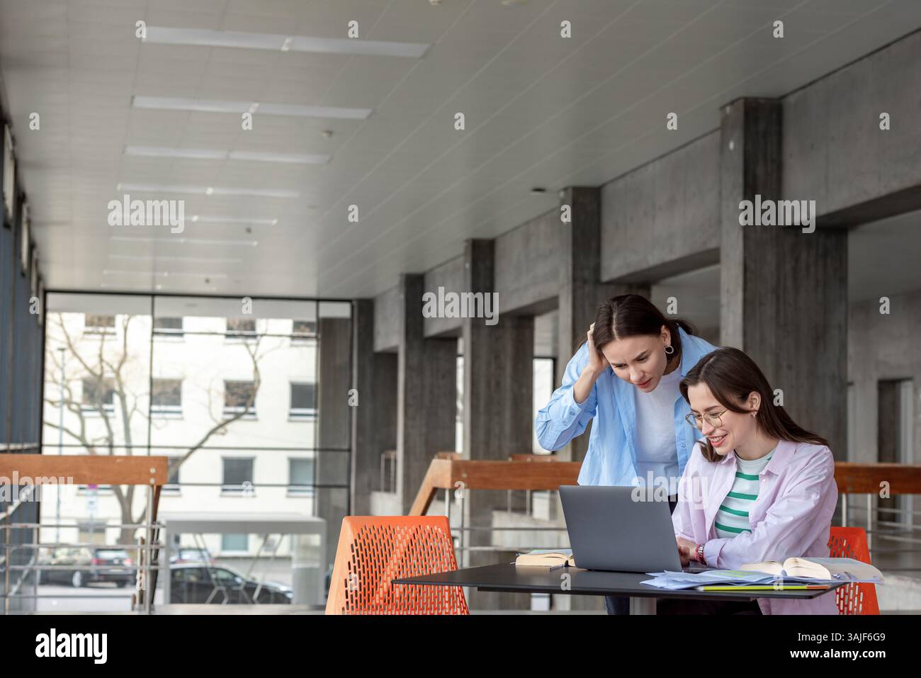 Two young female students work together on the laptop in the university lobby Stock Photo - Alamy
