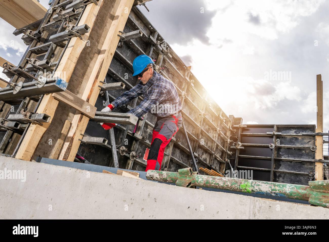 A construction worker in a blue helmet prepares concrete formwork at a building site during the ...