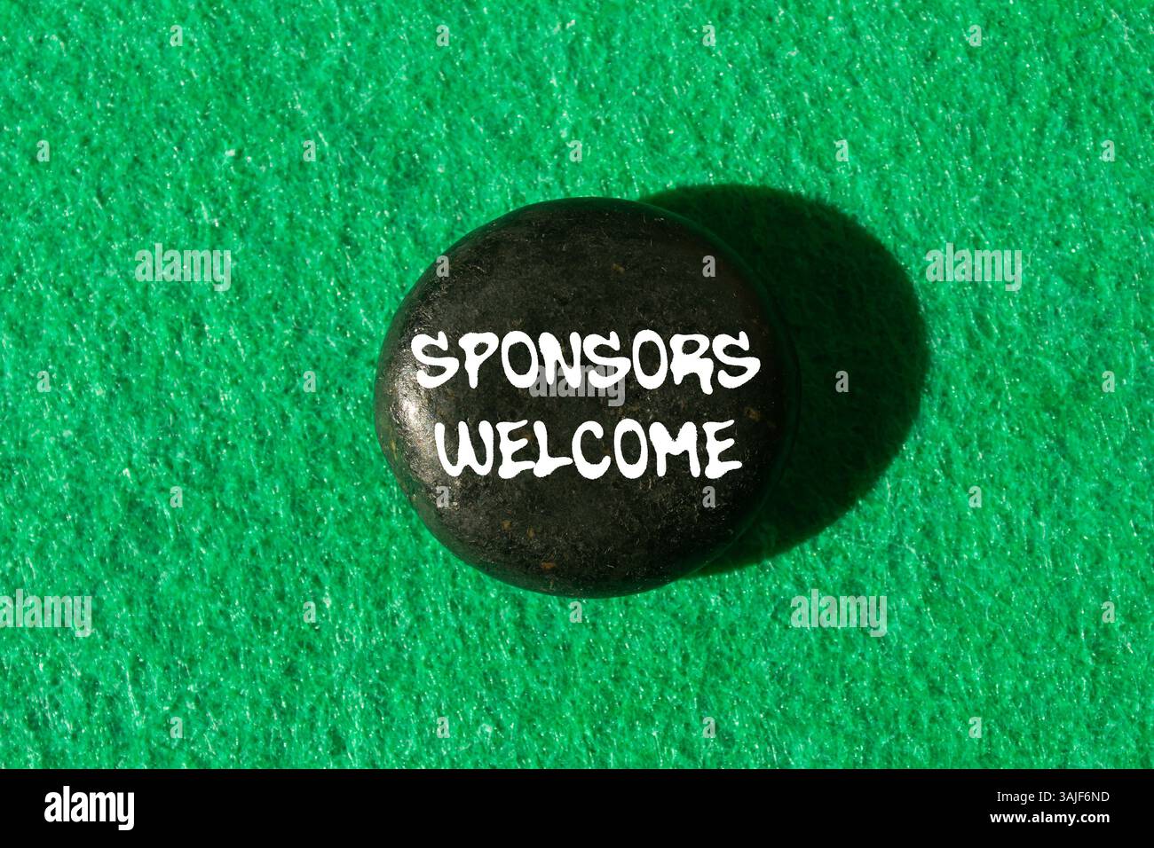 Sponsors welcome message written on black stone on green background ...