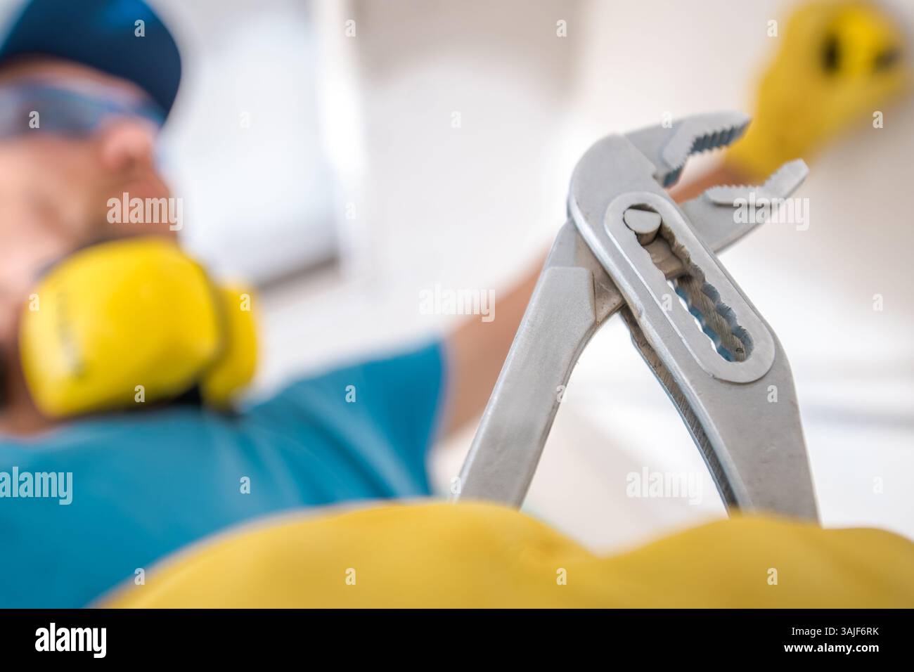 A skilled worker in a workshop focuses on a maintenance task. He wears ...