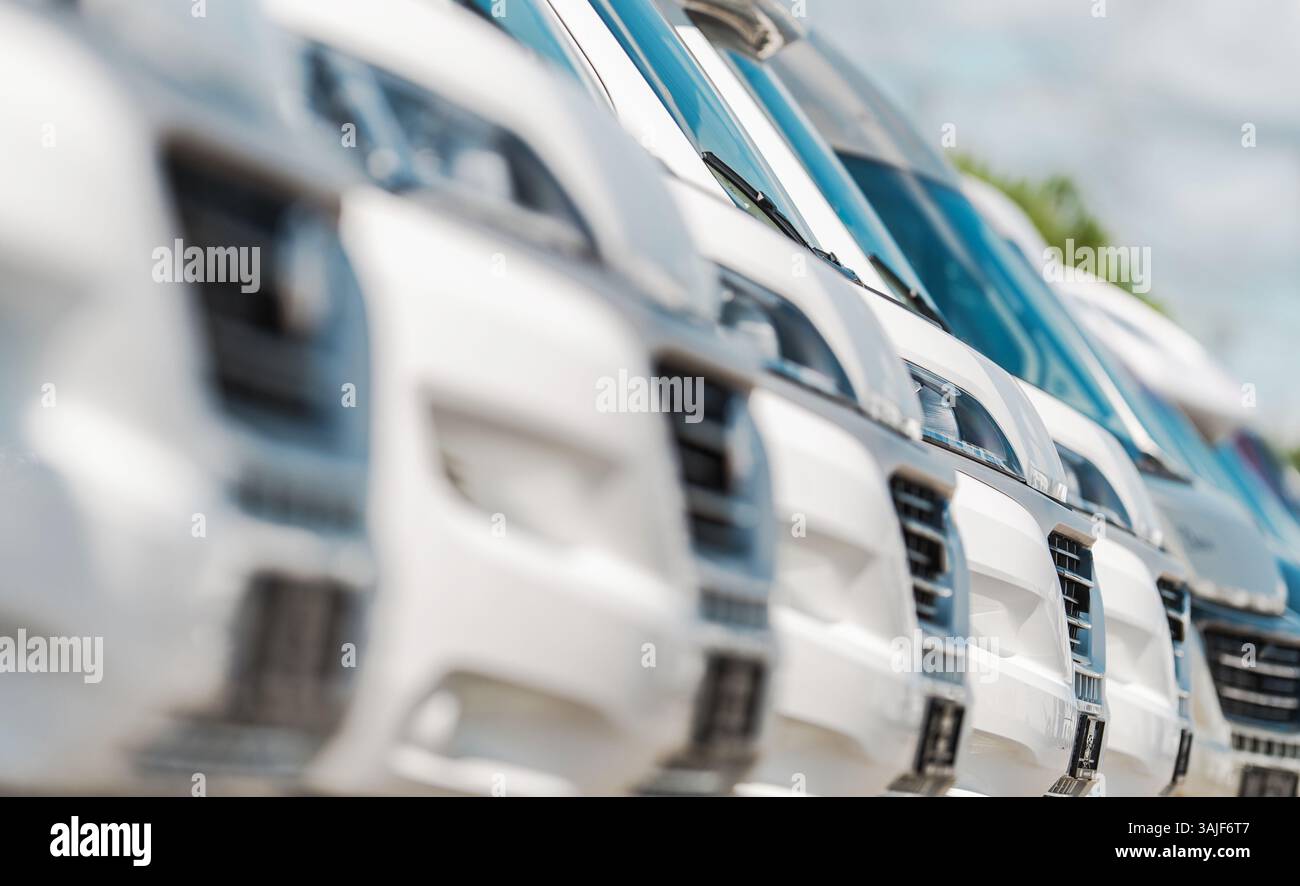 A row of white Motorhome Camper Van vehicles is neatly arranged in a ...