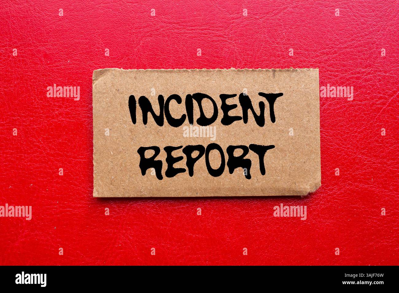 Incident report message written on ripped torn cardboard paper piece on red background ...