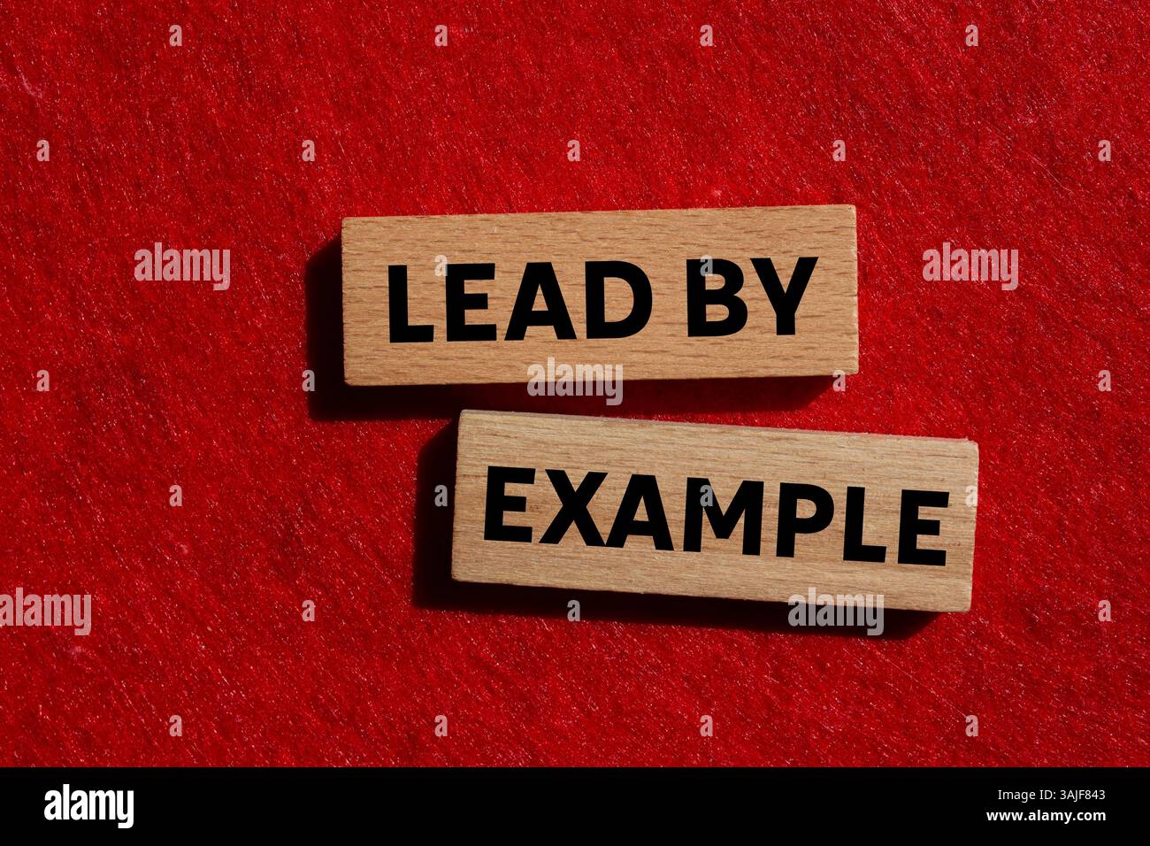Lead by example message written on wooden blocks on red background ...