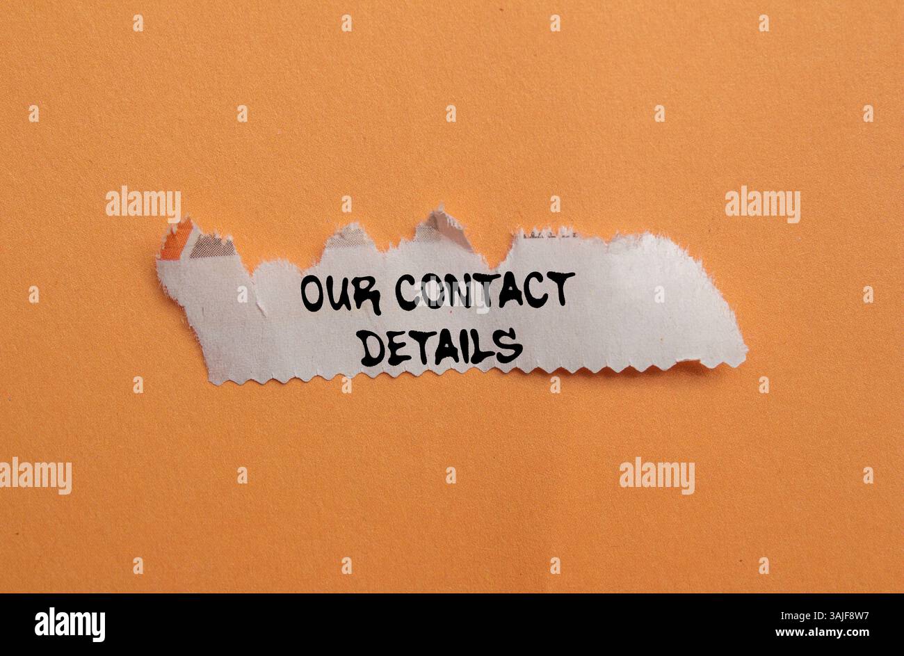 Our contact details message written on ripped torn newspaper piece on orange background ...
