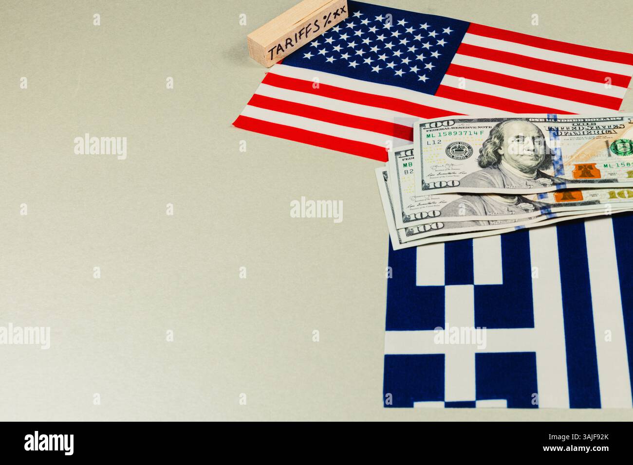 Flags of the USA and Greece lay on a surface alongside stacks of money ...