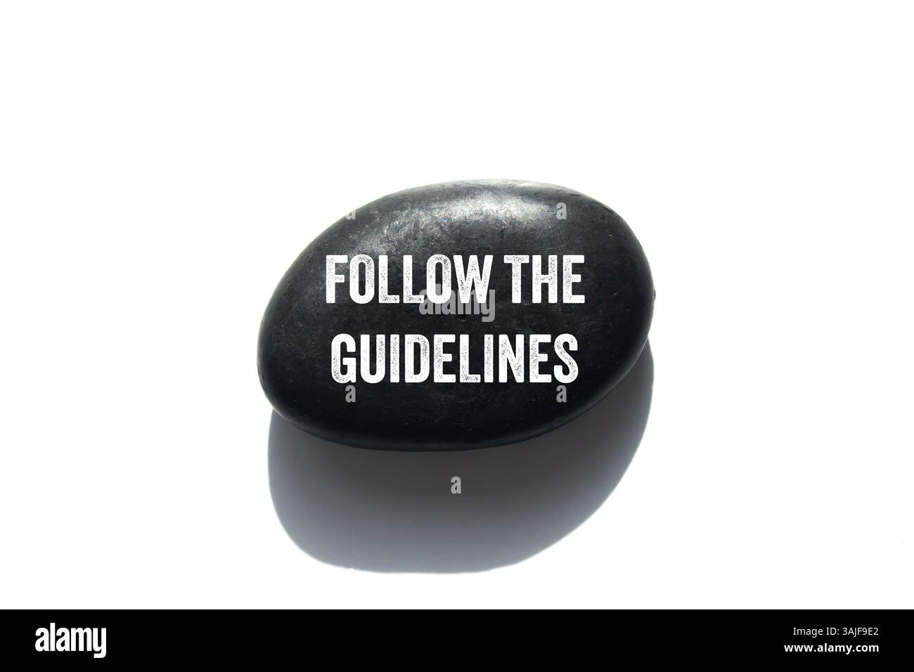 Follow the guidelines message written on black stone on white ...