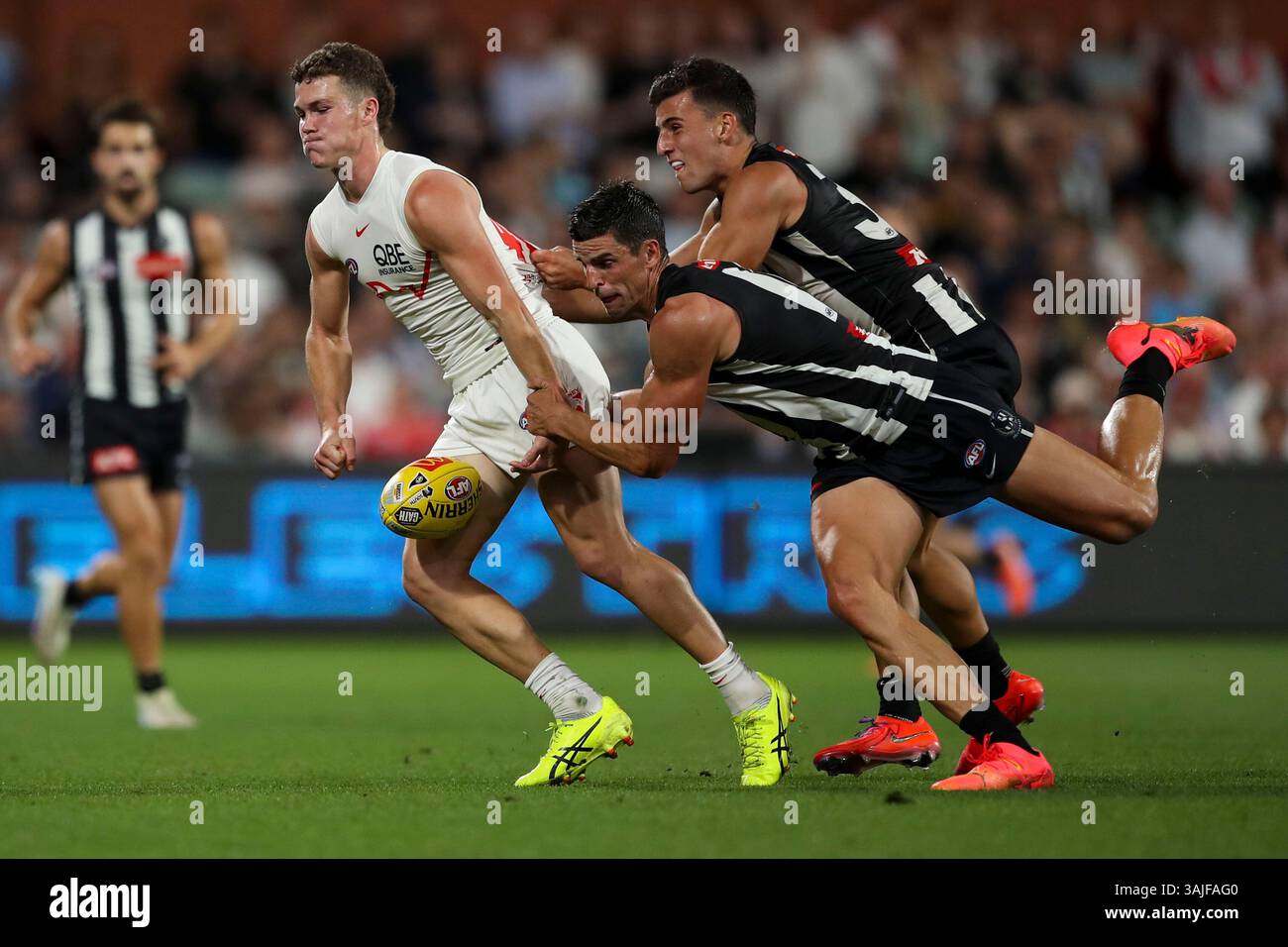 Tom Hanily of the Swans is tackled by Nick Daicos and Scott Pendlebury ...