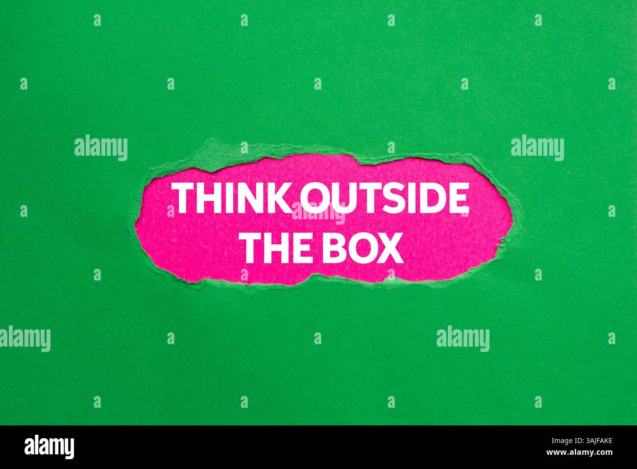 Think outside the box message written on ripped torn green paper on pink background. Conceptual ...