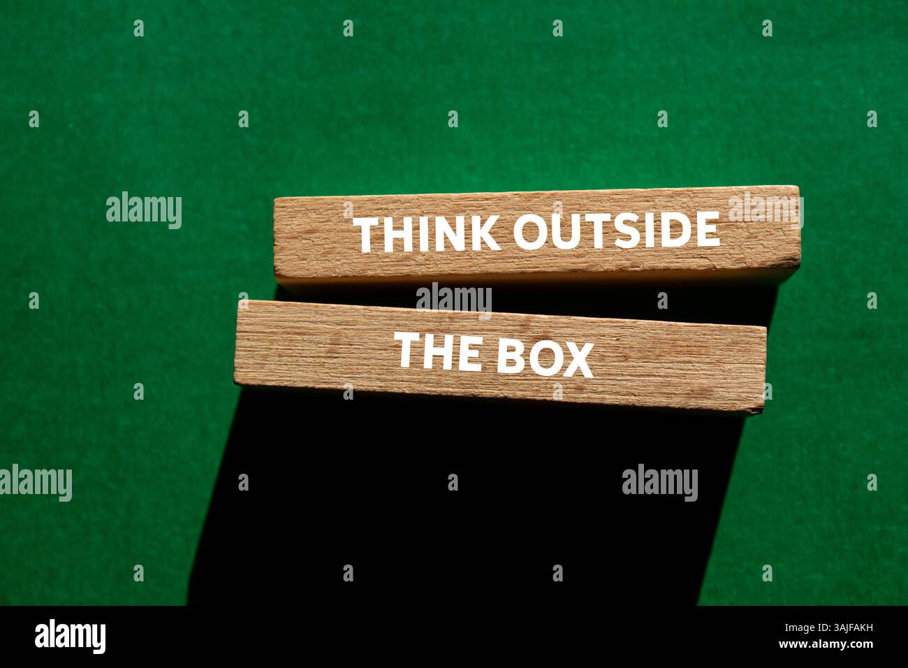 Think outside the box message written on wooden blocks on green background. Conceptual think ...