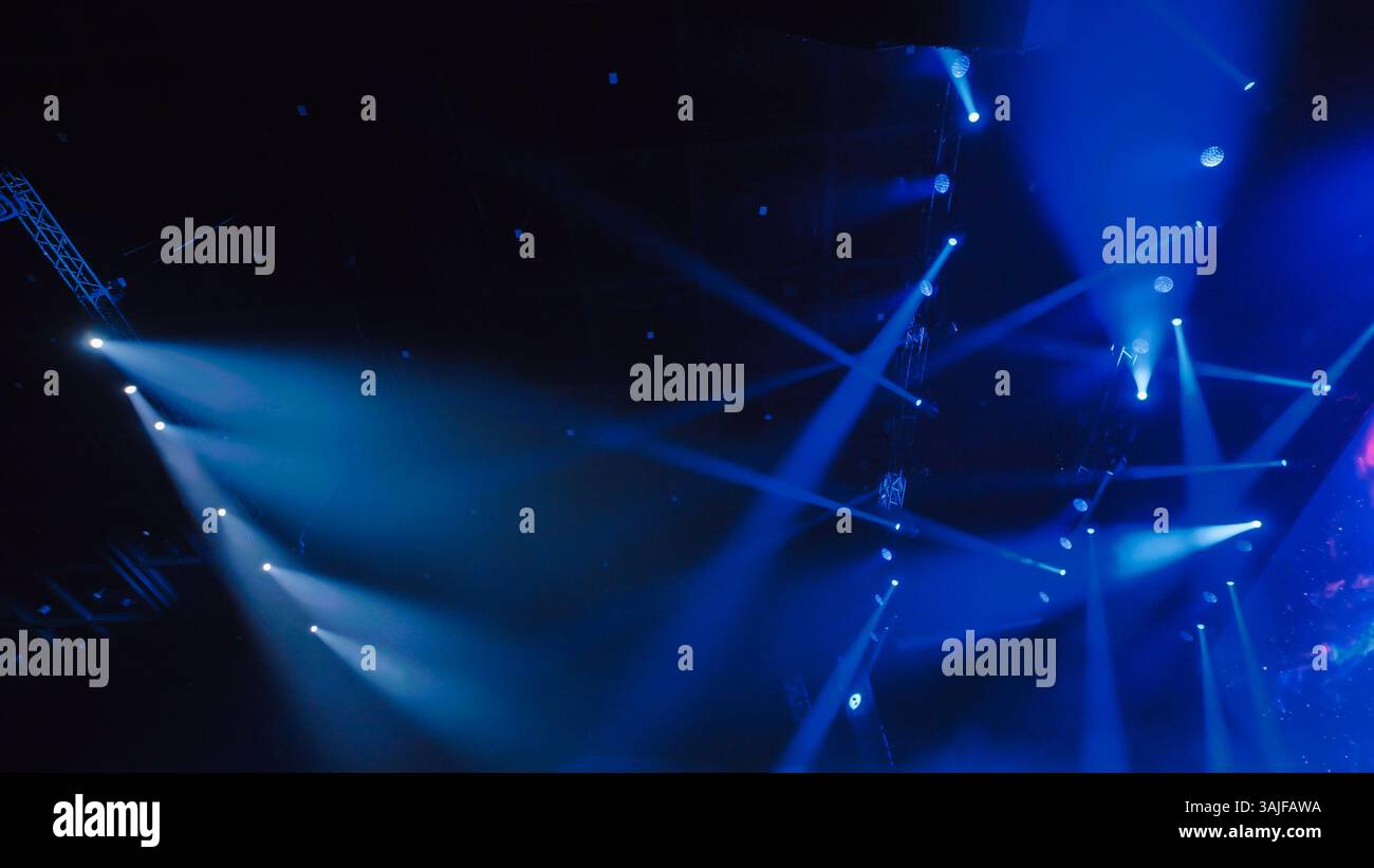 Blue stage lights illuminating dark concert hall during music festival ...