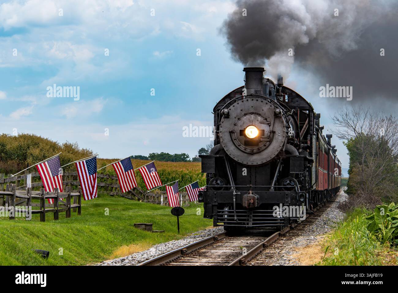 A classic steam train makes its way through a picturesque rural ...