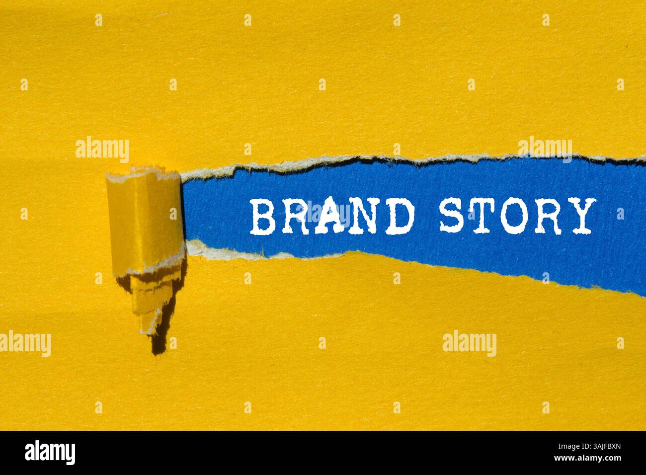Brand story message written on ripped torn yellow paper on blue ...