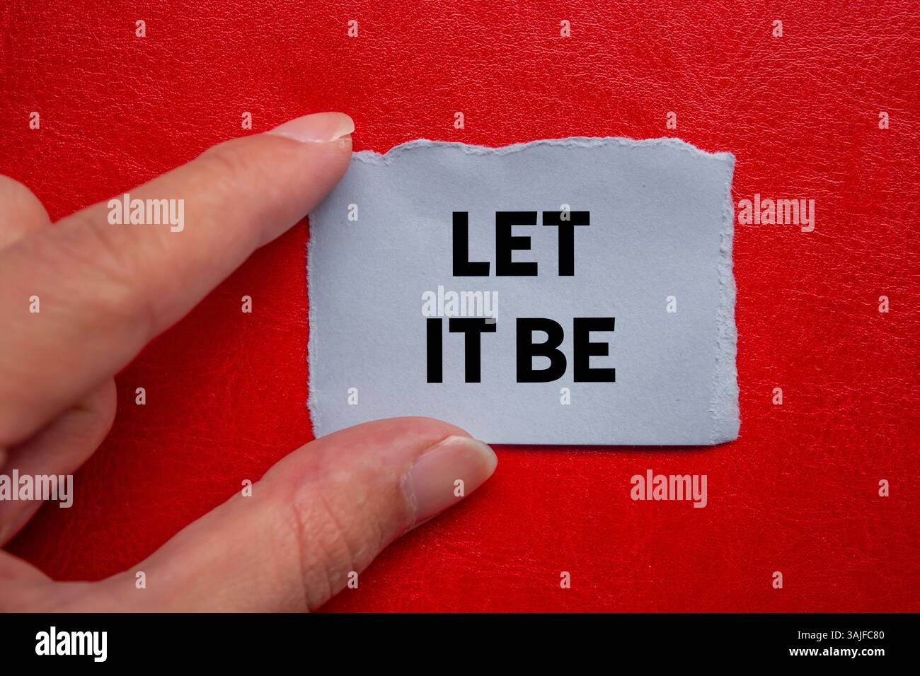 Let it be message written on ripped torn grey paper piece on red ...