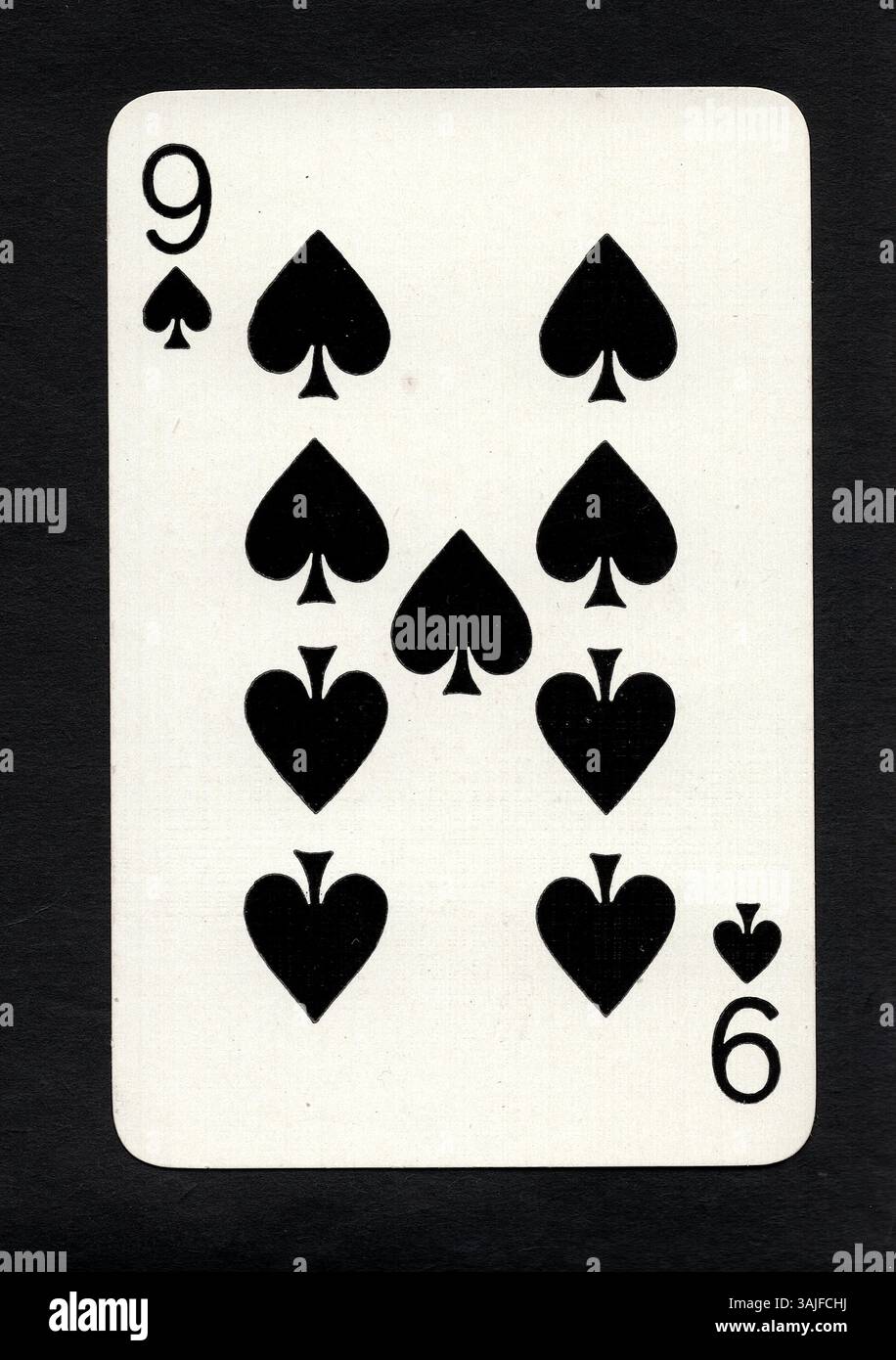 A vintage playing card in the suit of spades isolated on a black ...