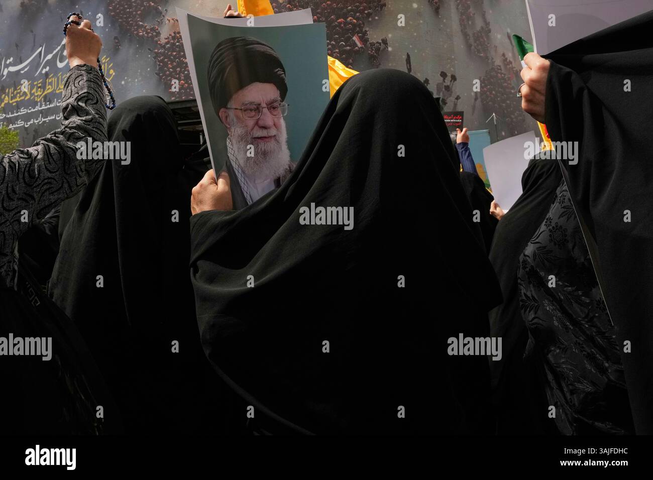 Iranian demonstrators chant slogans as one of them holds a poster of ...