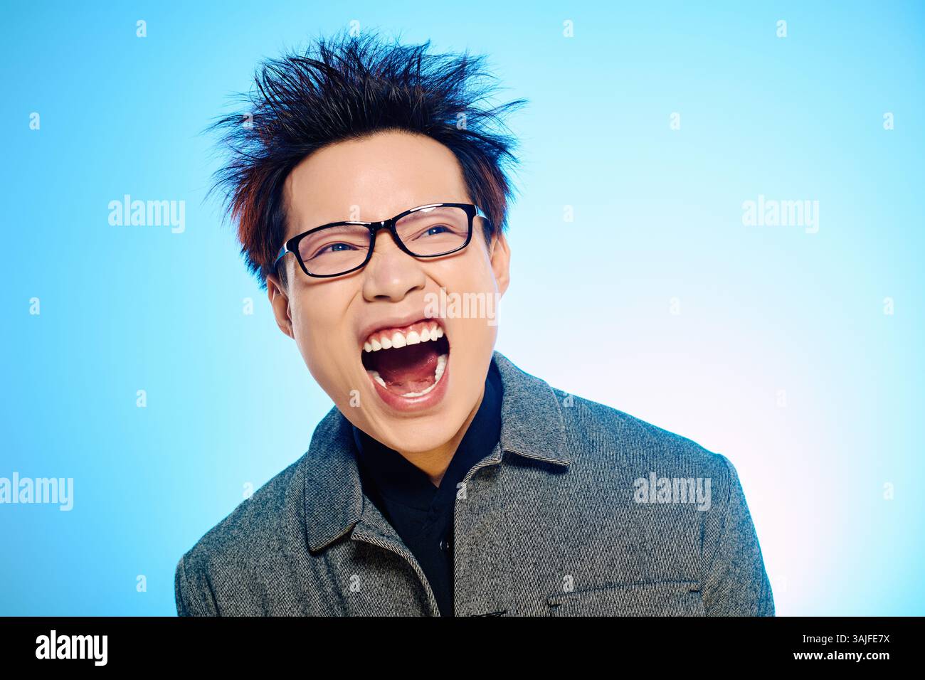 A cheerful young man with stylish hair expresses happiness while ...