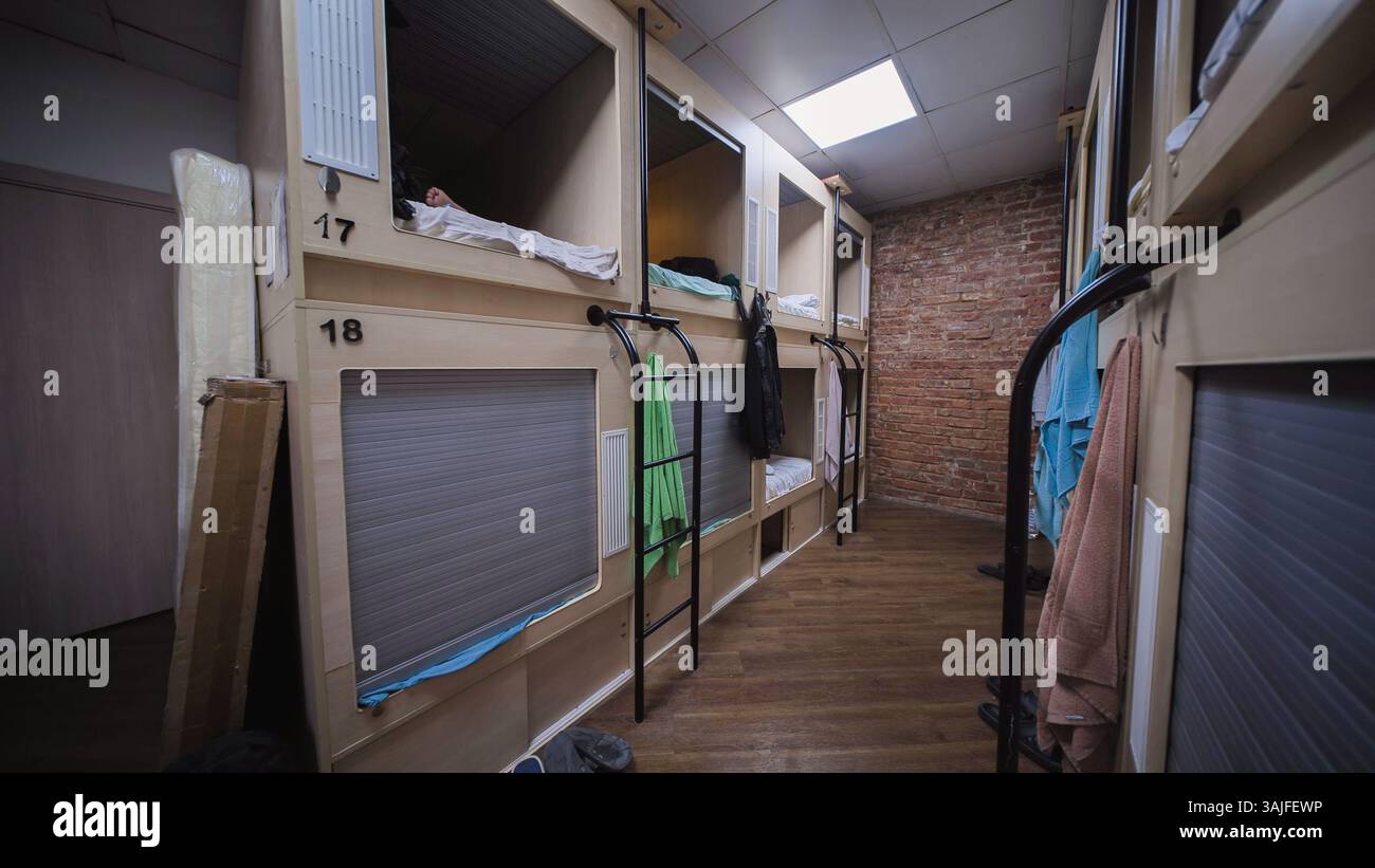 Hostel guest sleeping in pod bed with privacy rolling shutter door ...