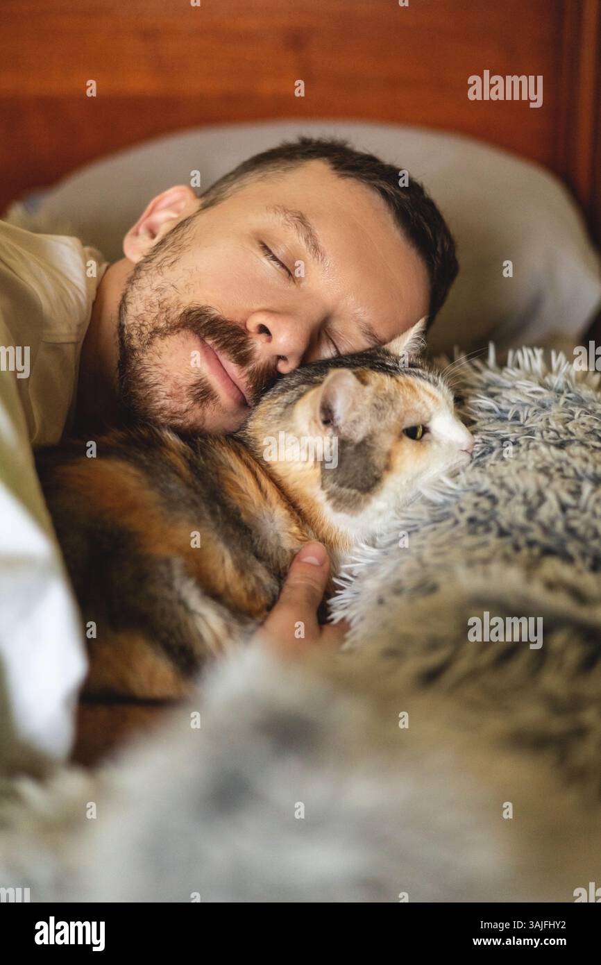 young guy hugging his favorite cat in bed Stock Photo - Alamy