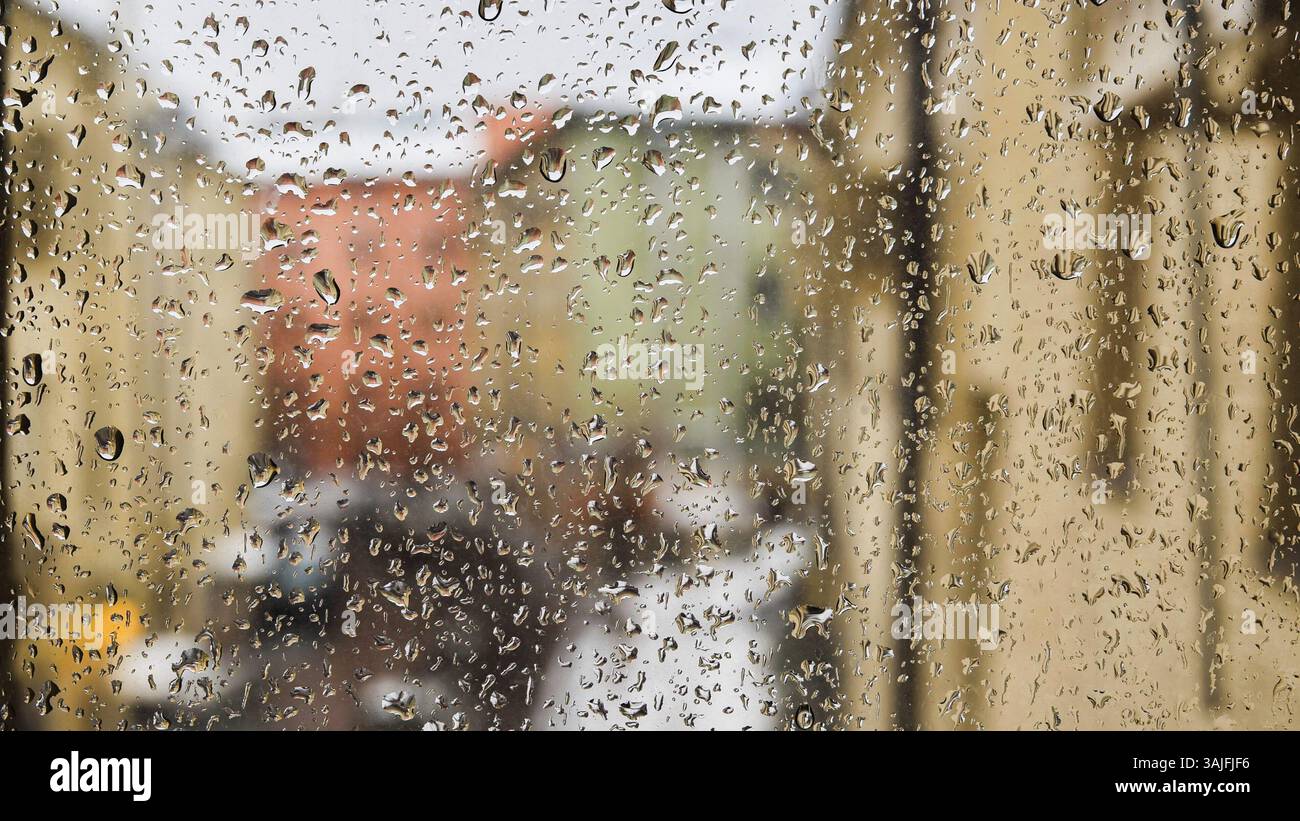 Raindrops sliding on window glass blurring cityscape view Stock Photo - Alamy