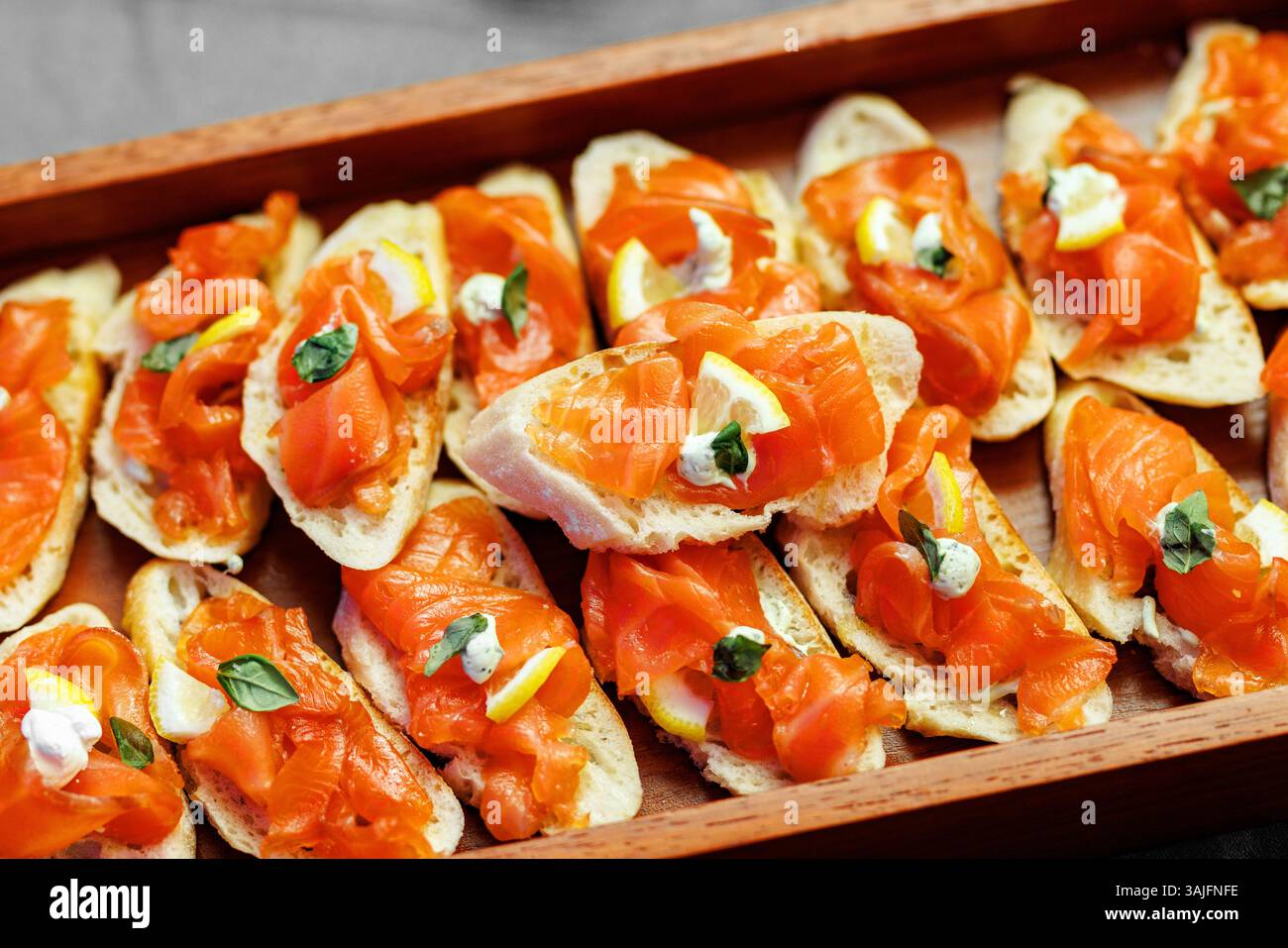 A tray of salmon and cheese appetizers. The appetizers are cut in half ...