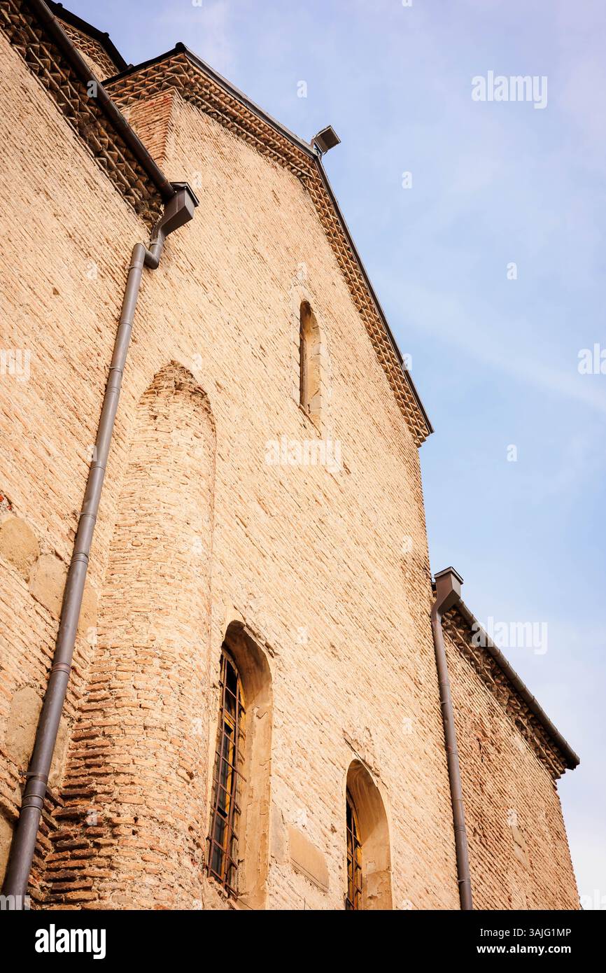 Upward view of an ancient brick church wall with arched windows and ...