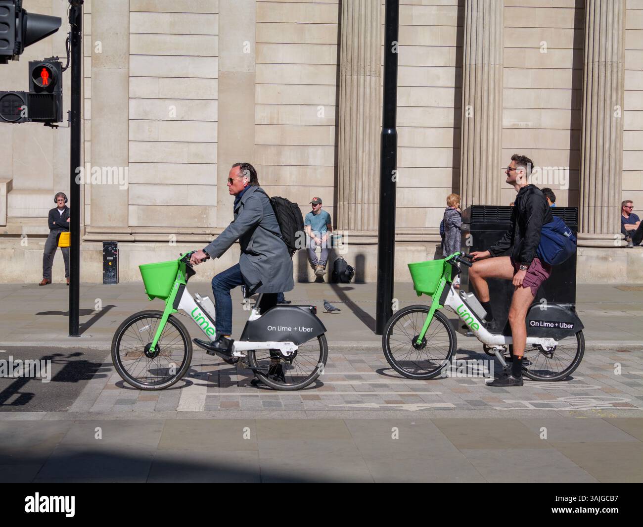 Male cyclists on Rental Lime Bike, e-bikes, queue at traffic lights ...