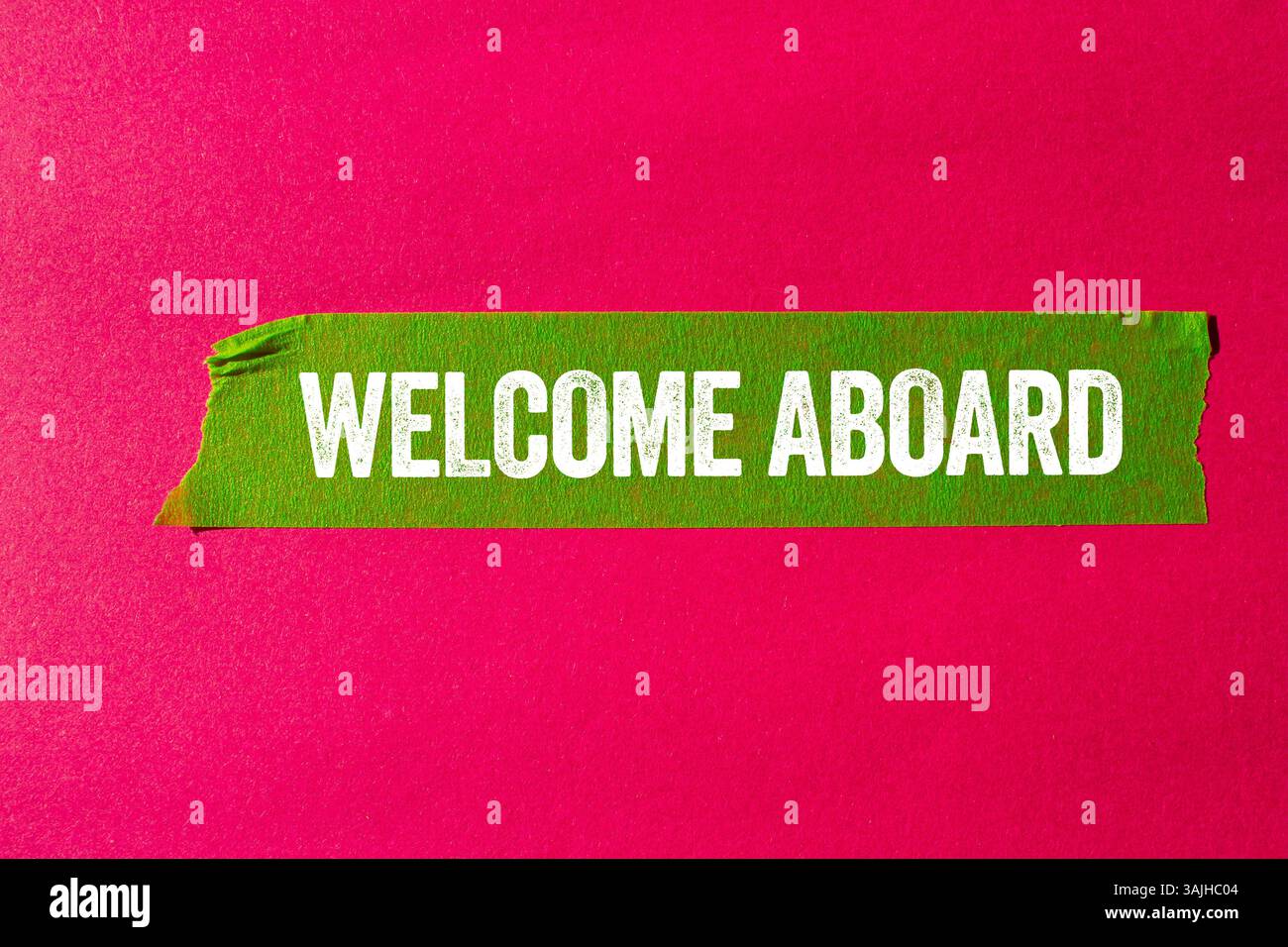 Welcome aboard message written on ripped torn green paper tape on pink ...