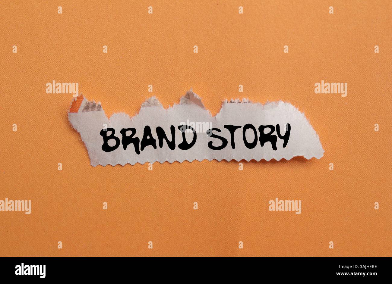 Brand story message written on ripped torn newspaper piece on orange ...