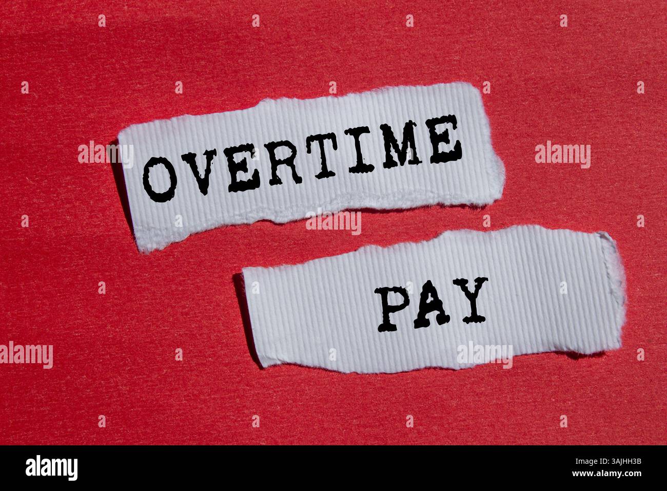Overtime pay message written on ripped torn white paper pieces on red ...