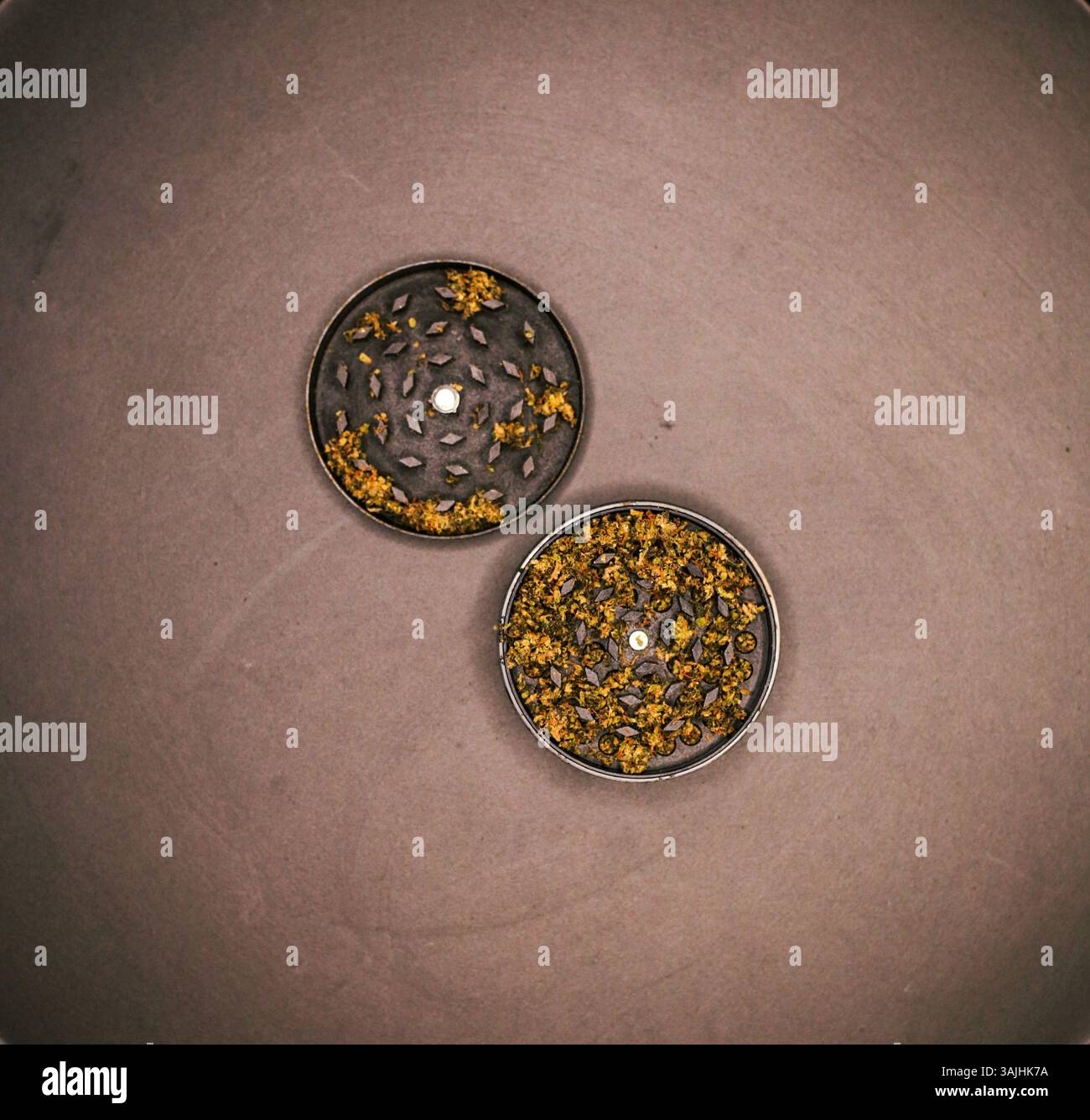 A close-up shot of a grinder filled with crushed cannabis on a black ...