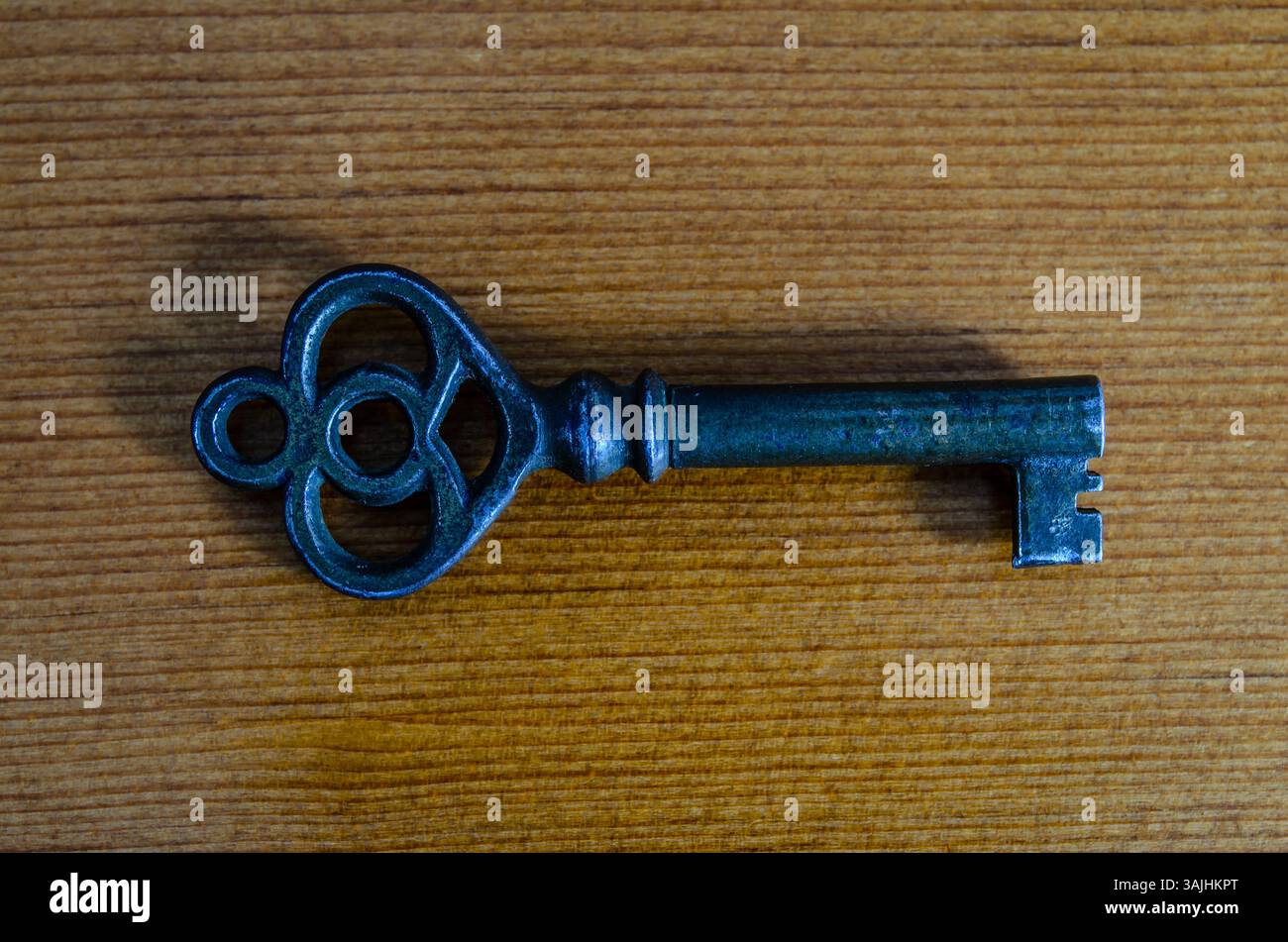Antique Blue Skeleton Key on Woodgrain Background, shown at a side view ...